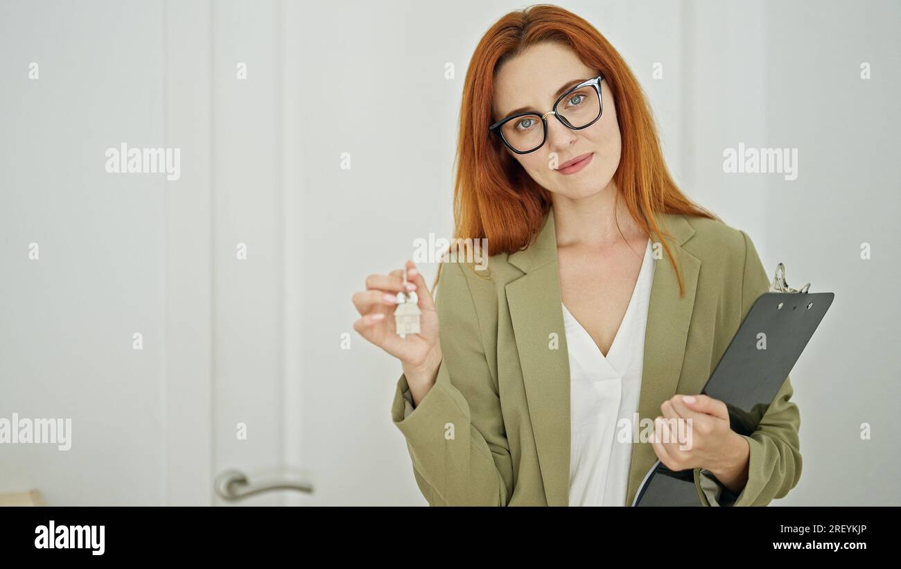 Young redhead woman real state agent holding keys at home Stock Photo ...