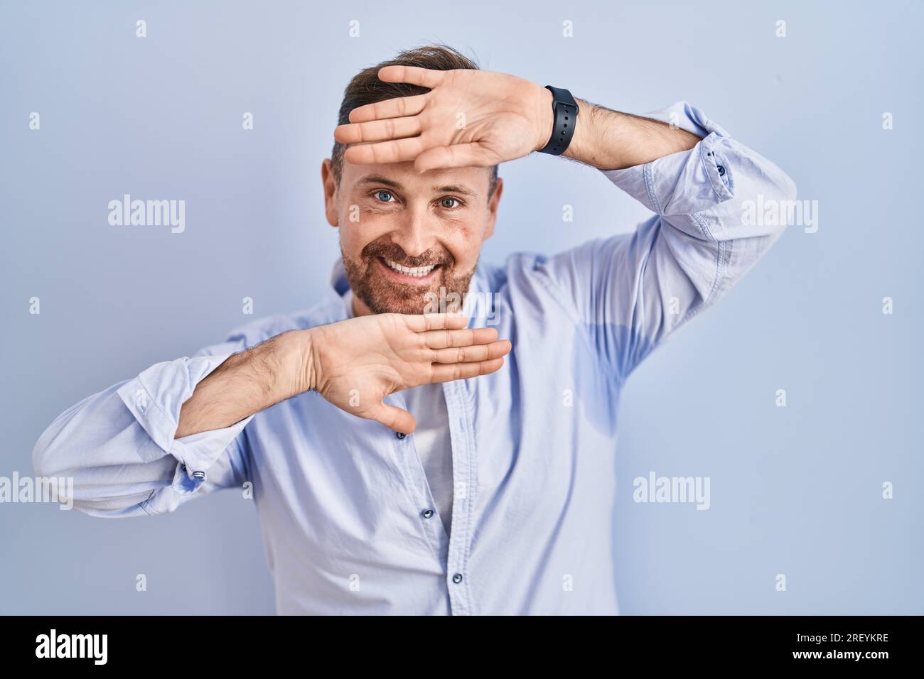 Middle age caucasian man standing over blue background smiling cheerful ...