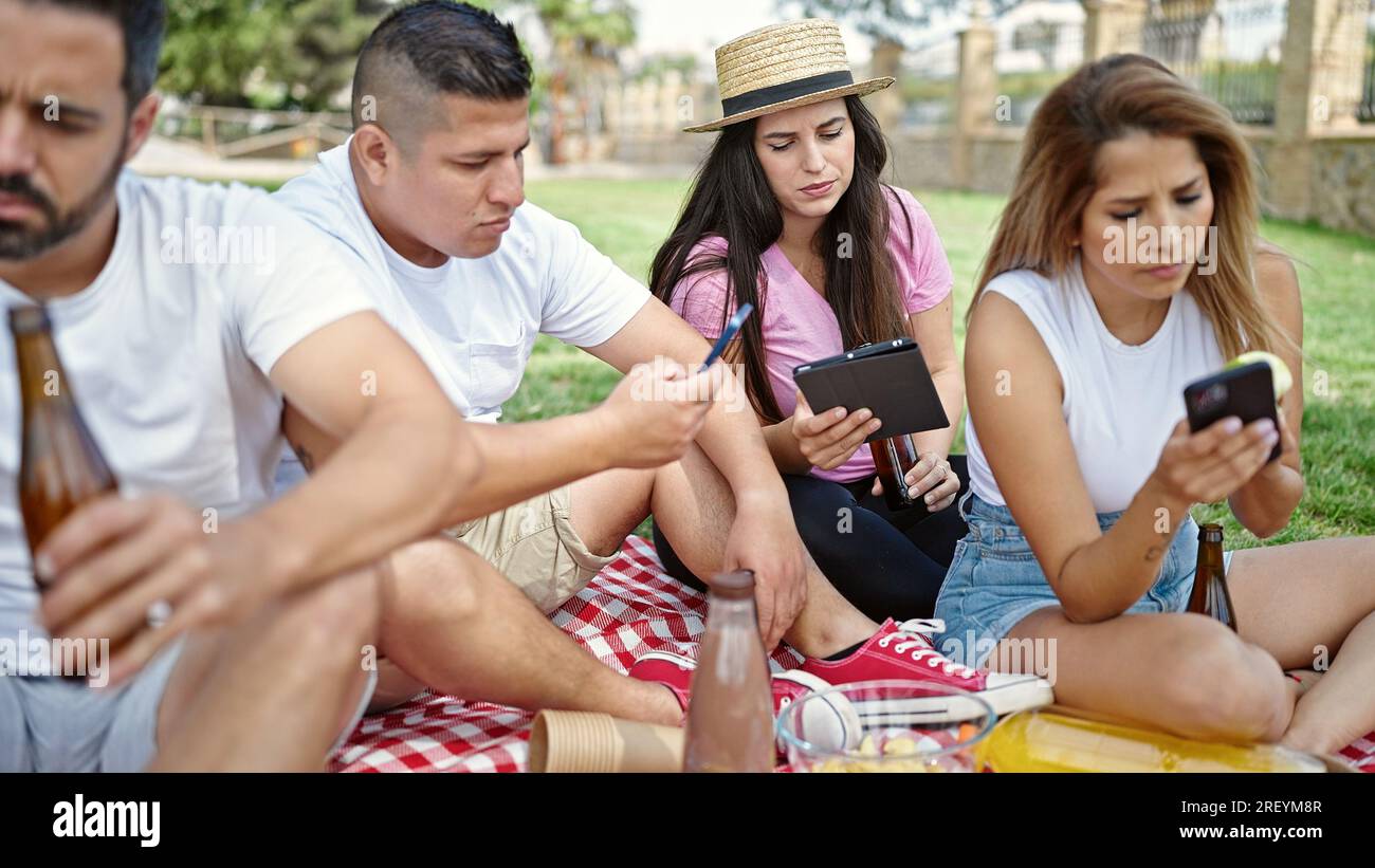 Group of people having picnic using smartphones and touchpad at park Stock Photo - Alamy