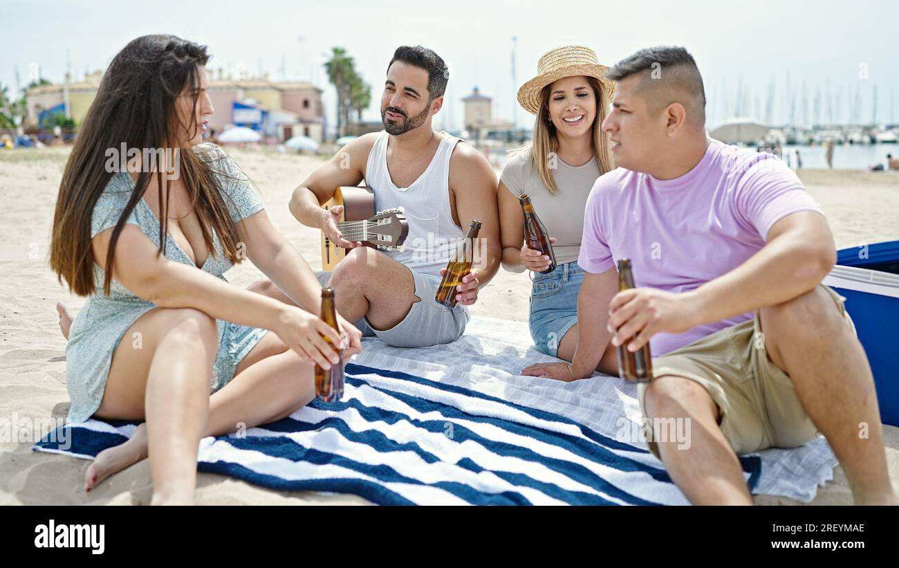 Group of people playing guitar drinking beer singing song at beach ...