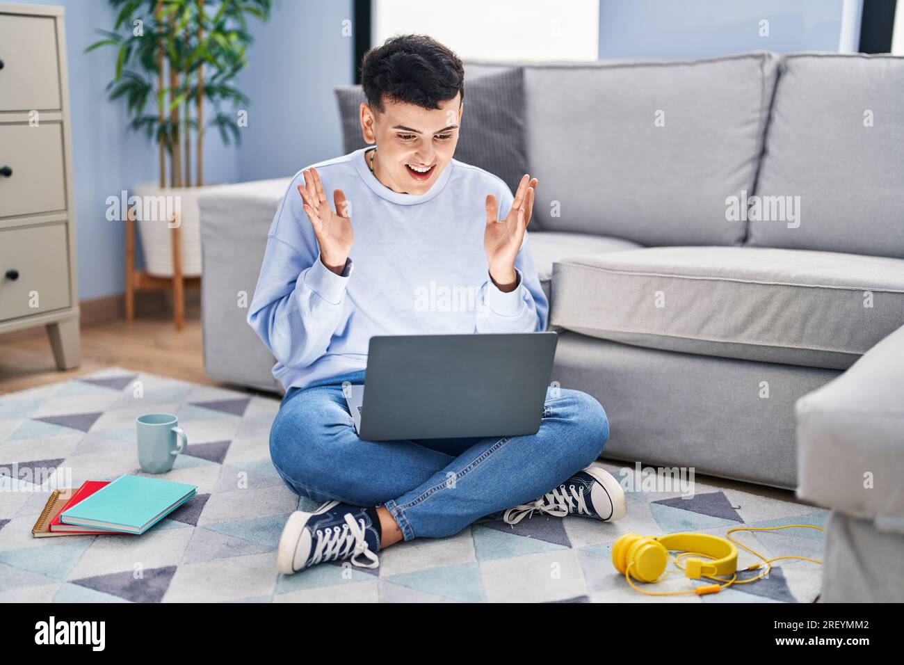 Non binary person studying using computer laptop sitting on the floor ...