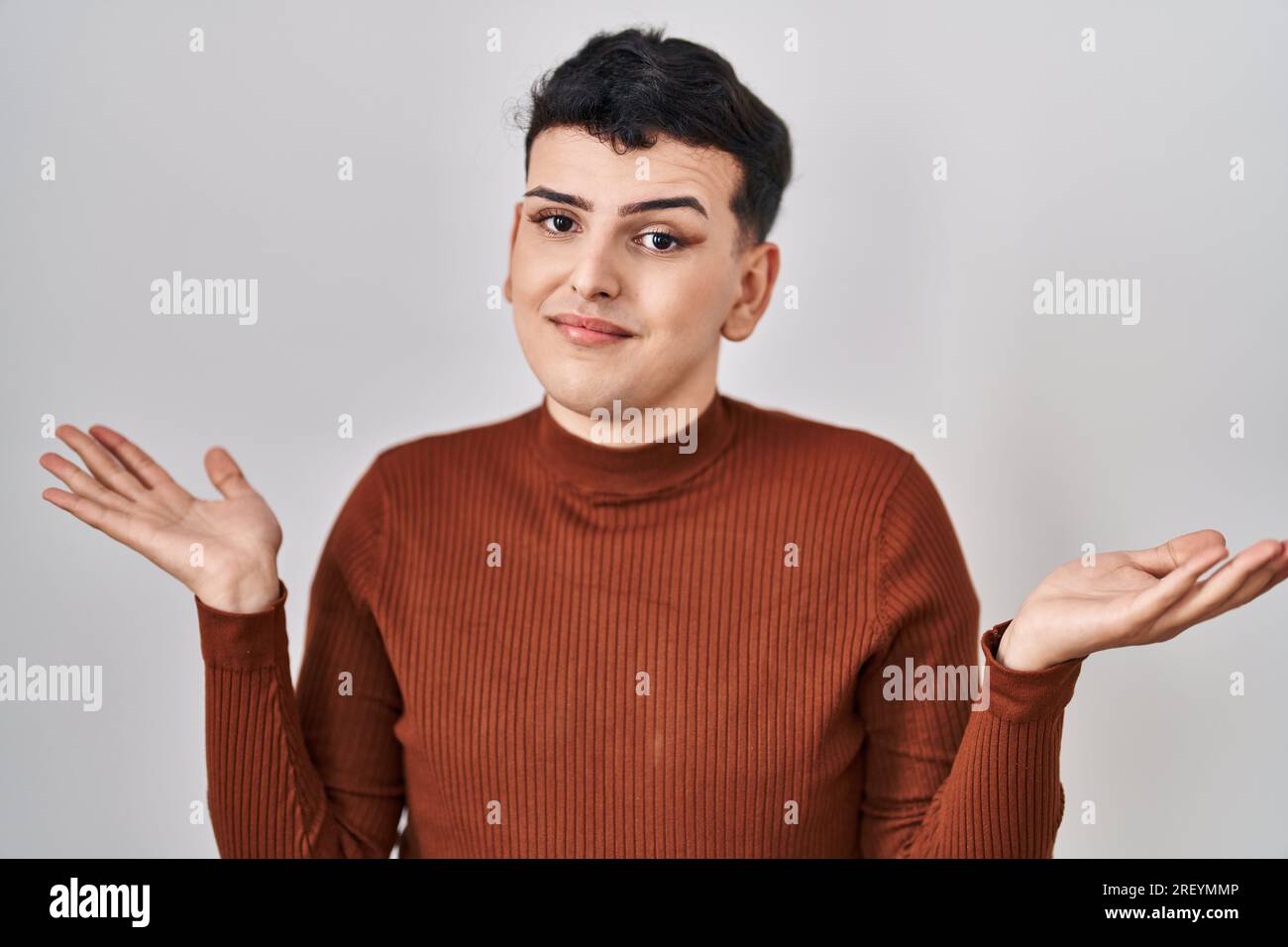 Non binary person wearing make up standing over isolated background ...