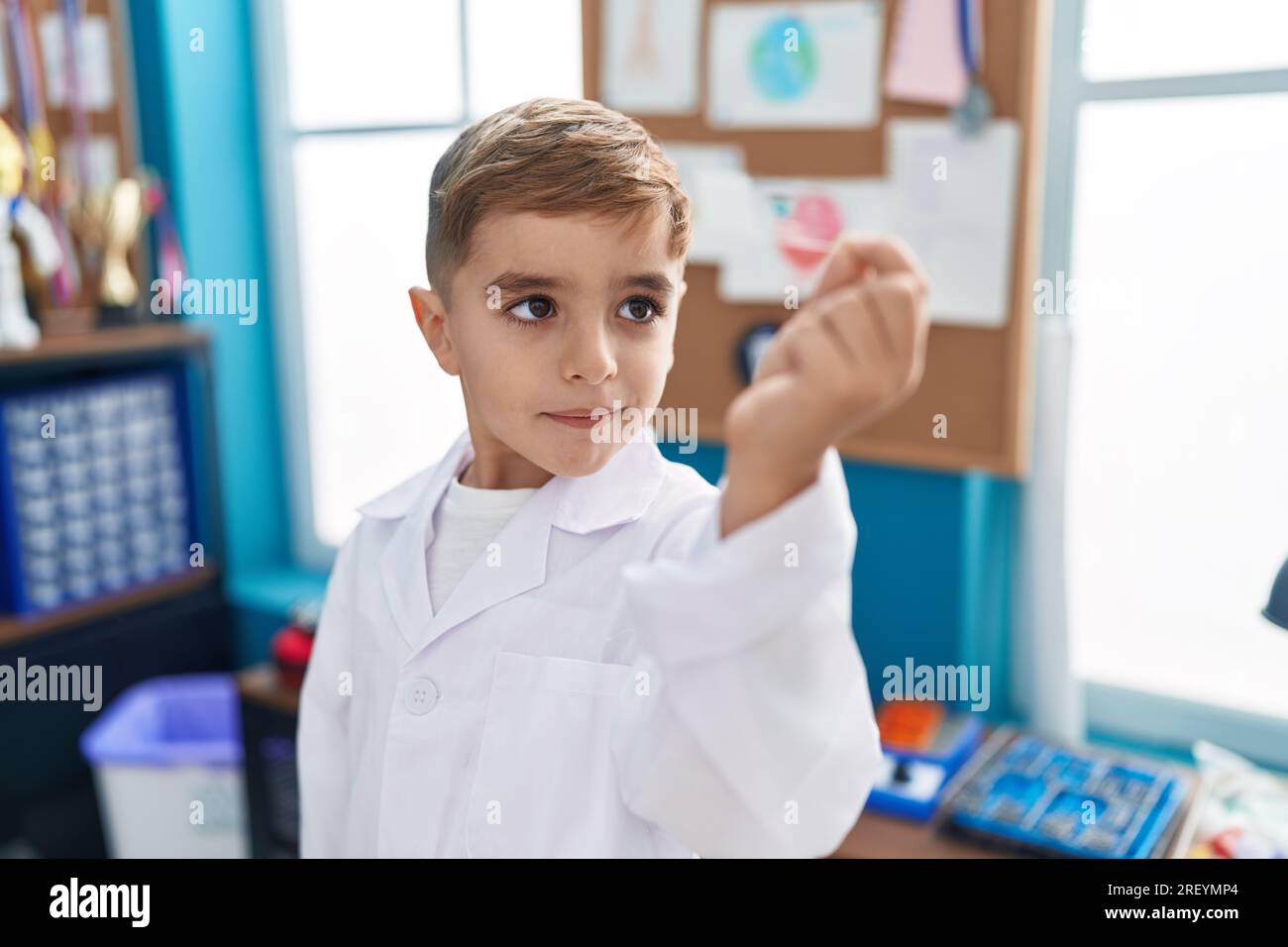 Adorable hispanic boy student looking sample at laboratory classroom ...