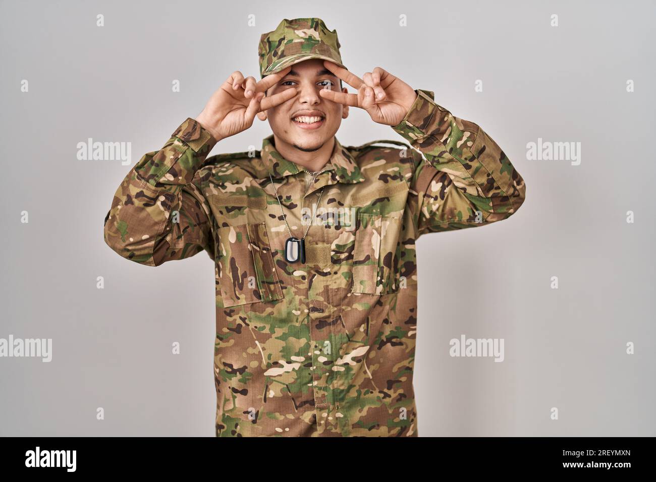 Young arab man wearing camouflage army uniform doing peace symbol with ...