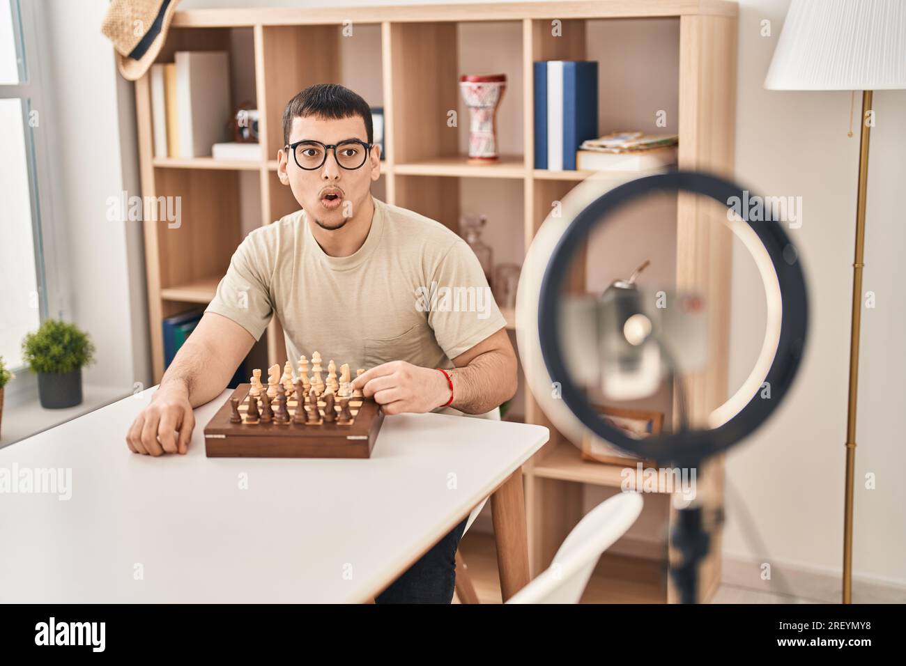 Young arab man doing chess tutorial scared and amazed with open mouth ...