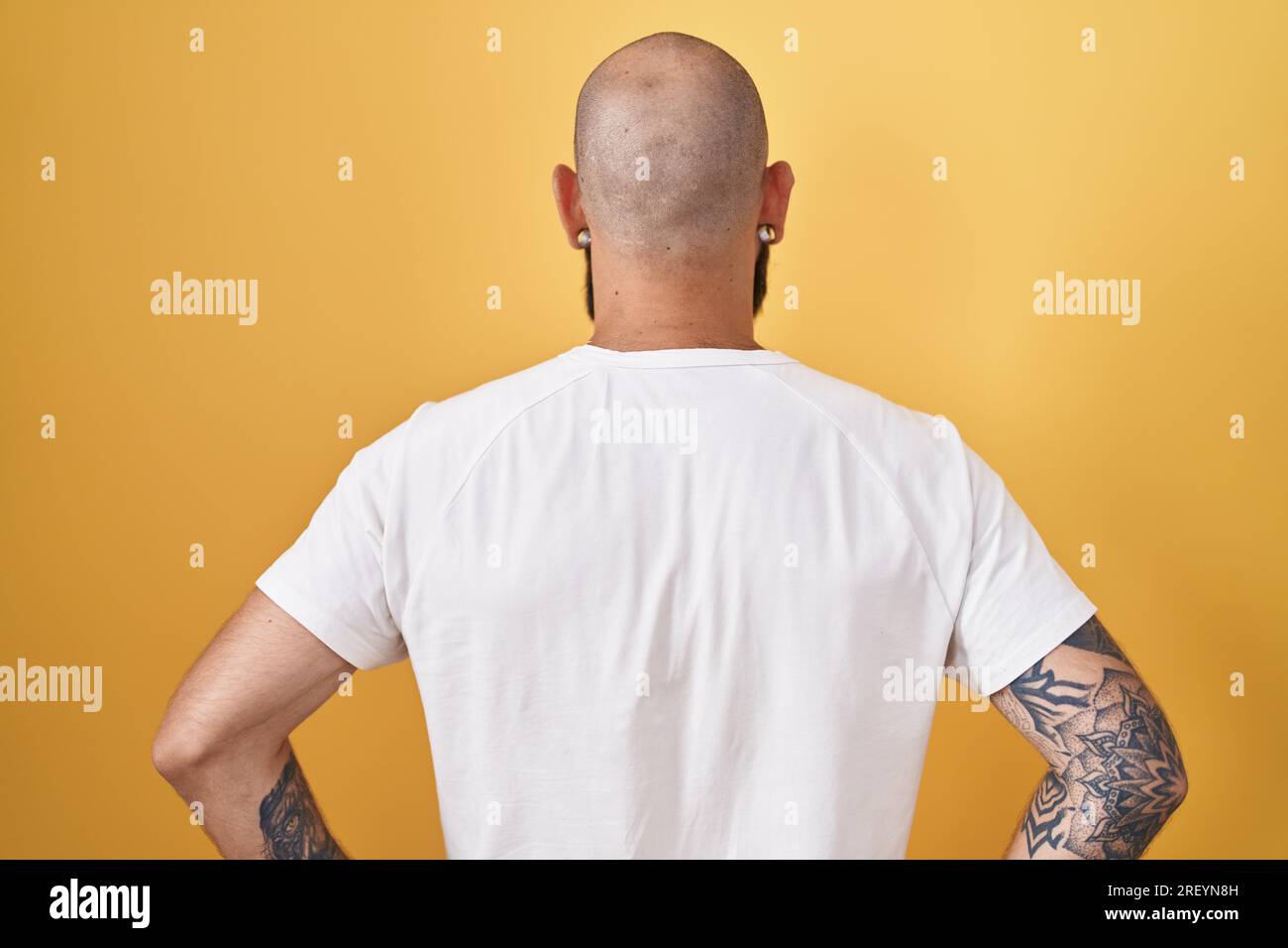Young hispanic man with beard and tattoos standing over yellow ...