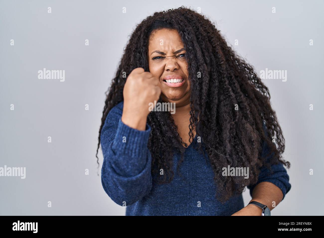 Plus size hispanic woman standing over white background angry and mad ...