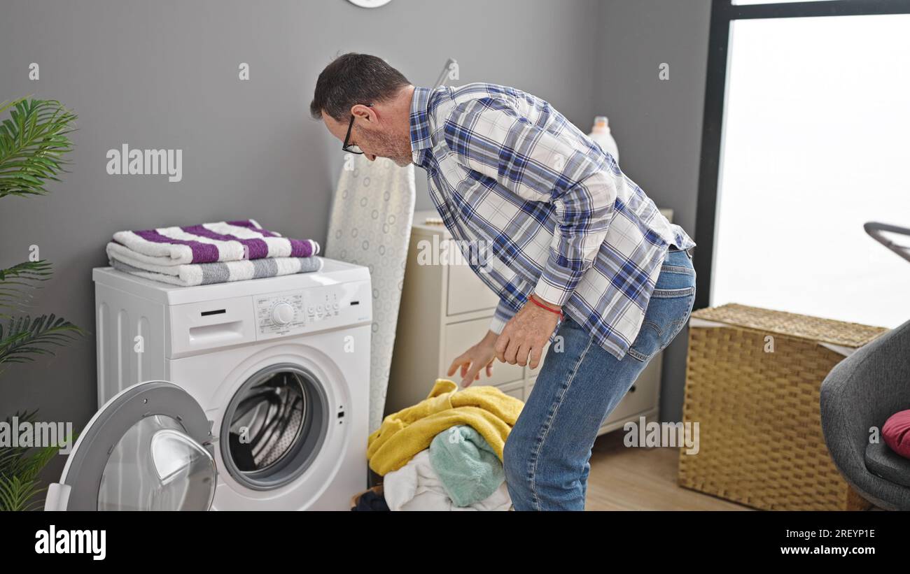Middle age man washing clothes at laundry room Stock Photo - Alamy