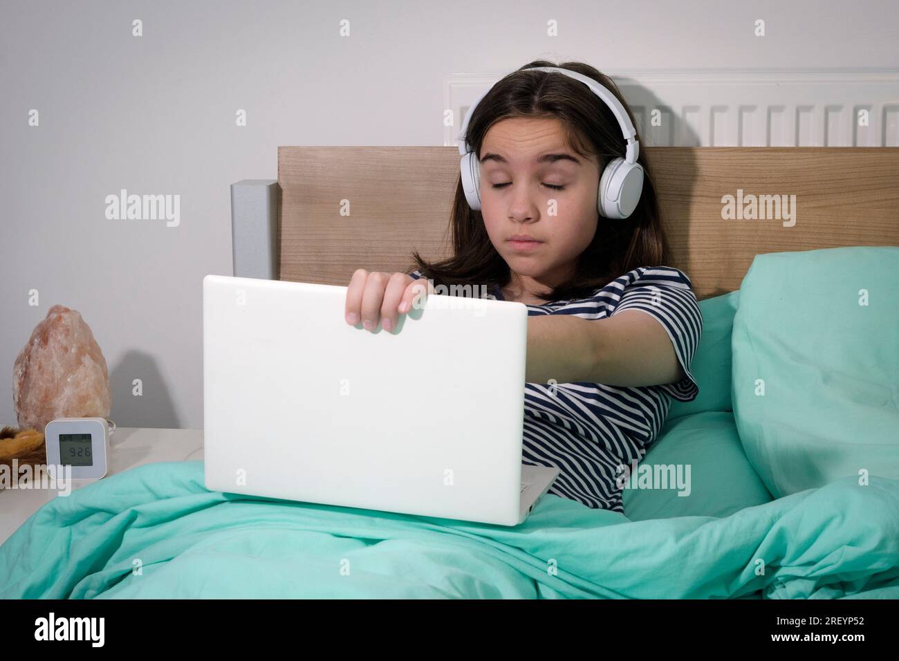 Tired of the computer in bed, the teen girl is going to sleep. Computer ...