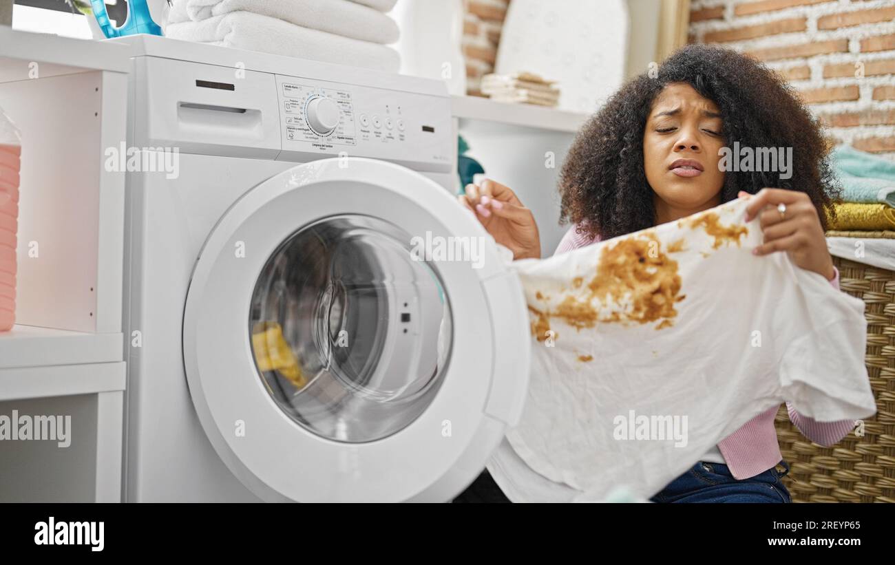 African american woman washing clothes holding dirty shirt looking ...