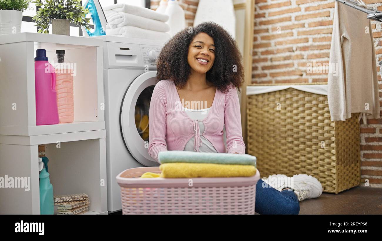 African american woman smiling confident washing clothes at laundry ...
