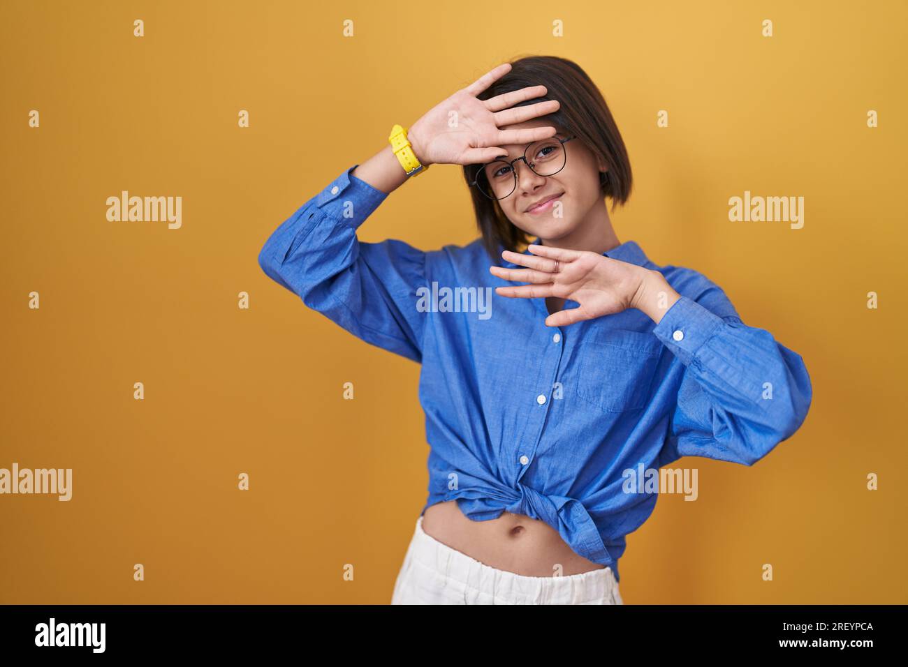 Young girl standing over yellow background smiling cheerful playing ...