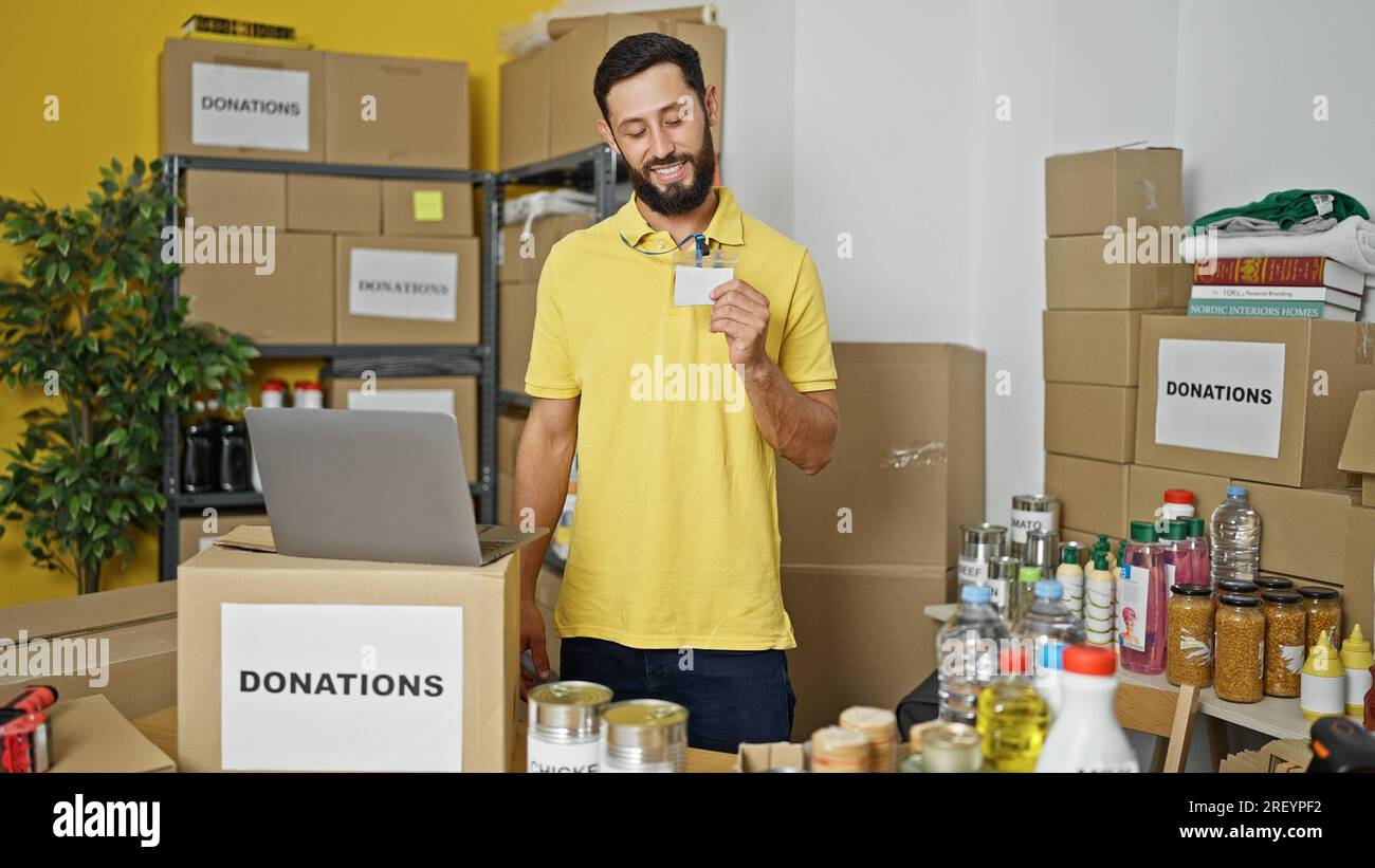 Young hispanic man volunteer holding id card at charity center Stock ...