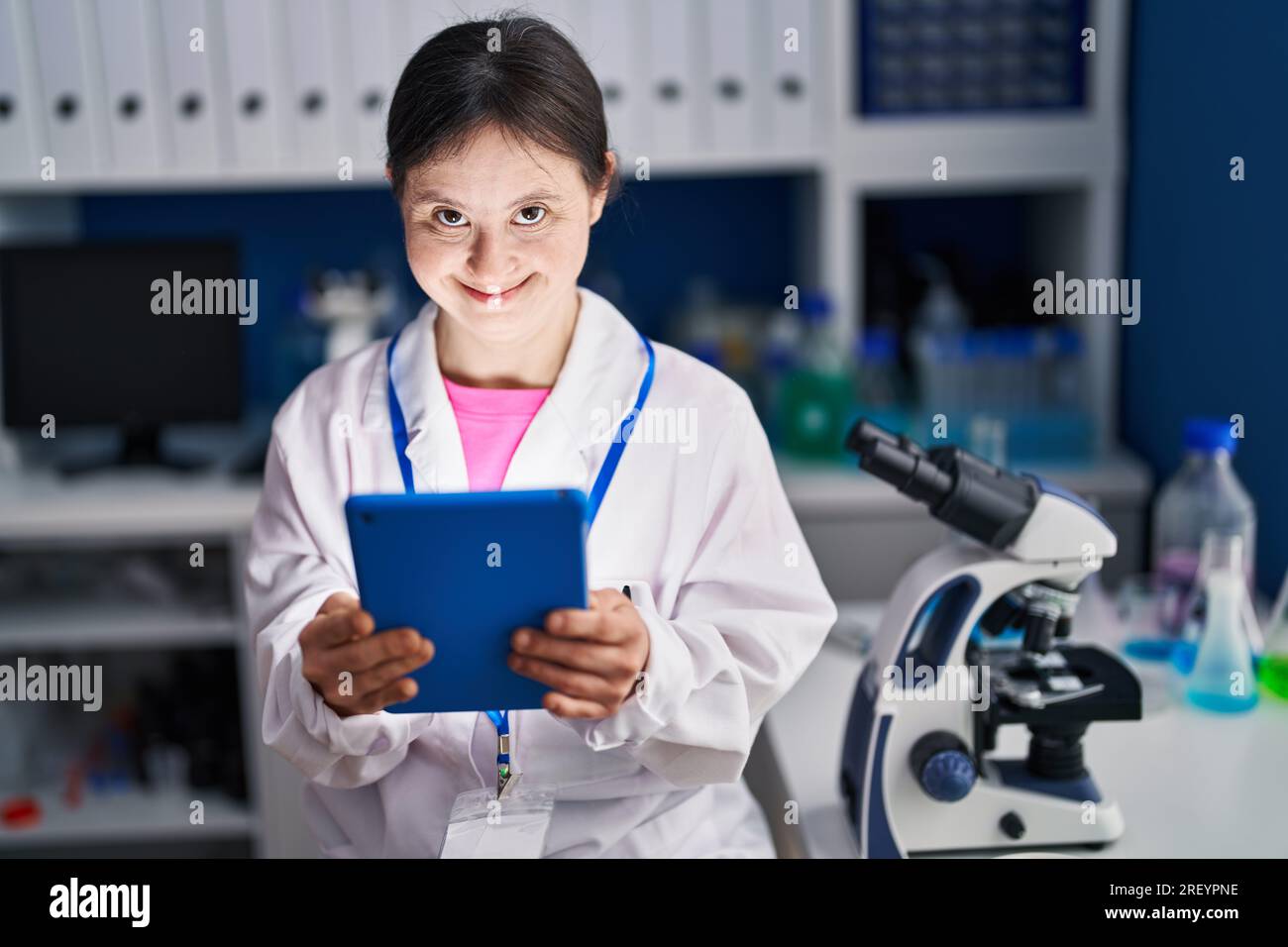 Young woman with down syndrome scientist smiling confident using touchpad at laboratory Stock ...