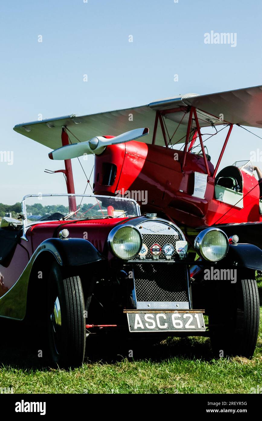 Vintage plane and car. Red Tiger Moth biplane with classic 1936 Morgan ...