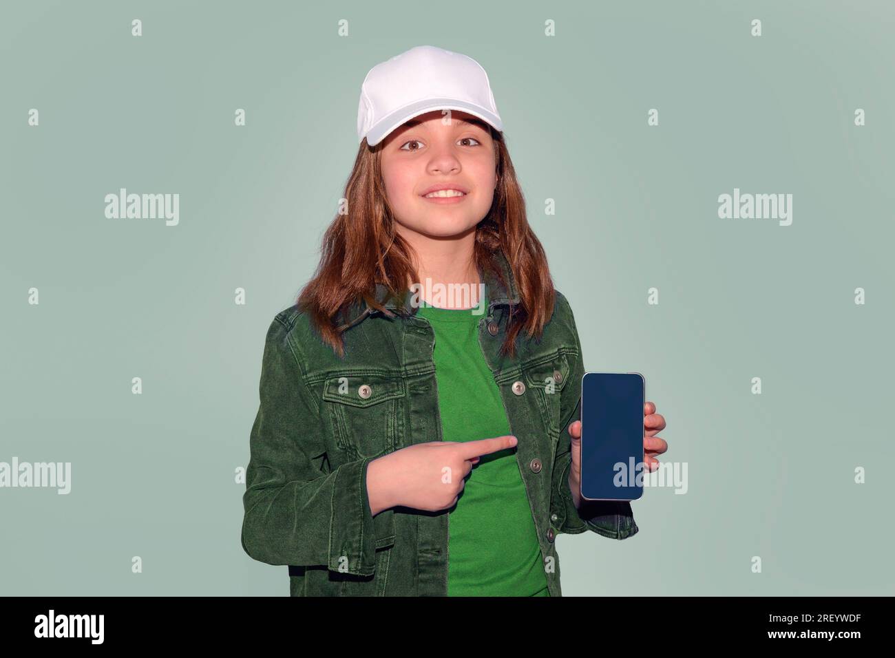 A teenage girl shows the screen of her smartphone. White baseball cap ...
