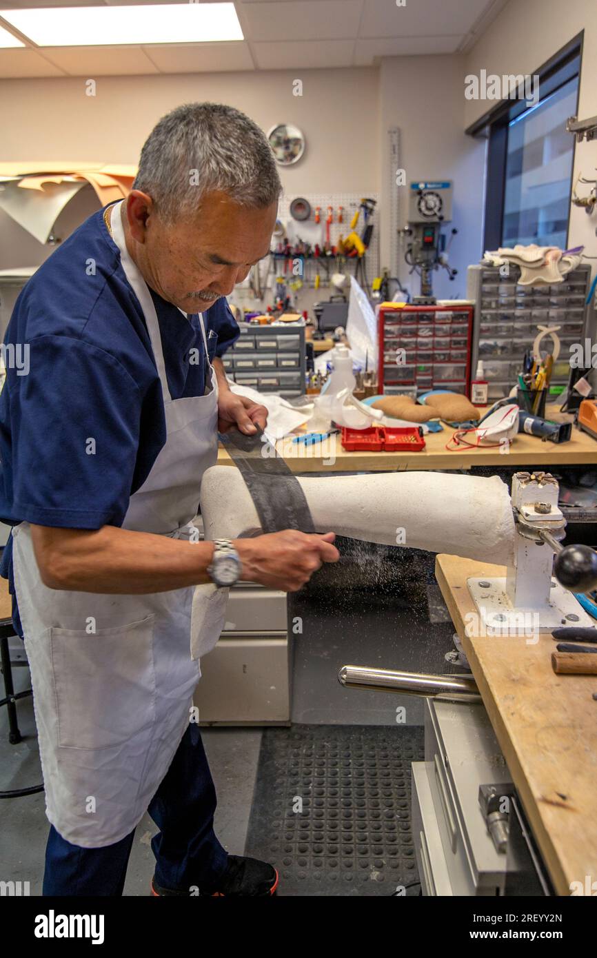 A Japanese-American technician sands a cast of a leg for a custom made ...