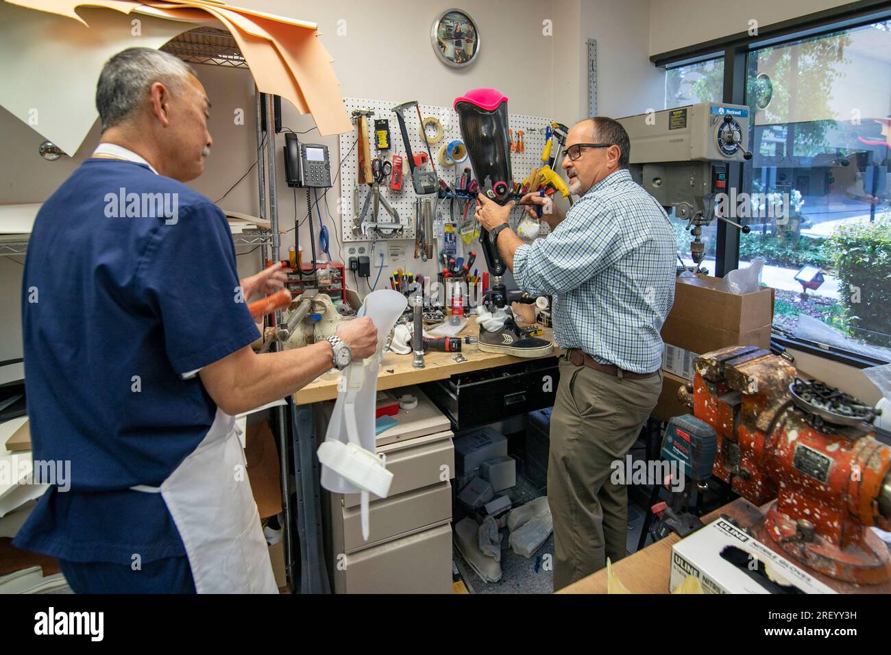 Technicians work on a prosthetic ankle brace and a prosthetic leg at a ...
