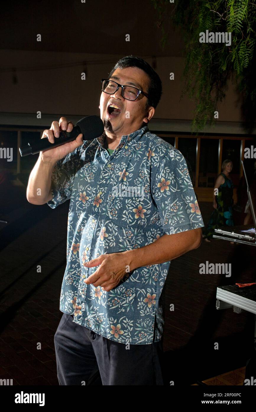 An Asian American Catholic priest sings at an informal outdoor summer ...