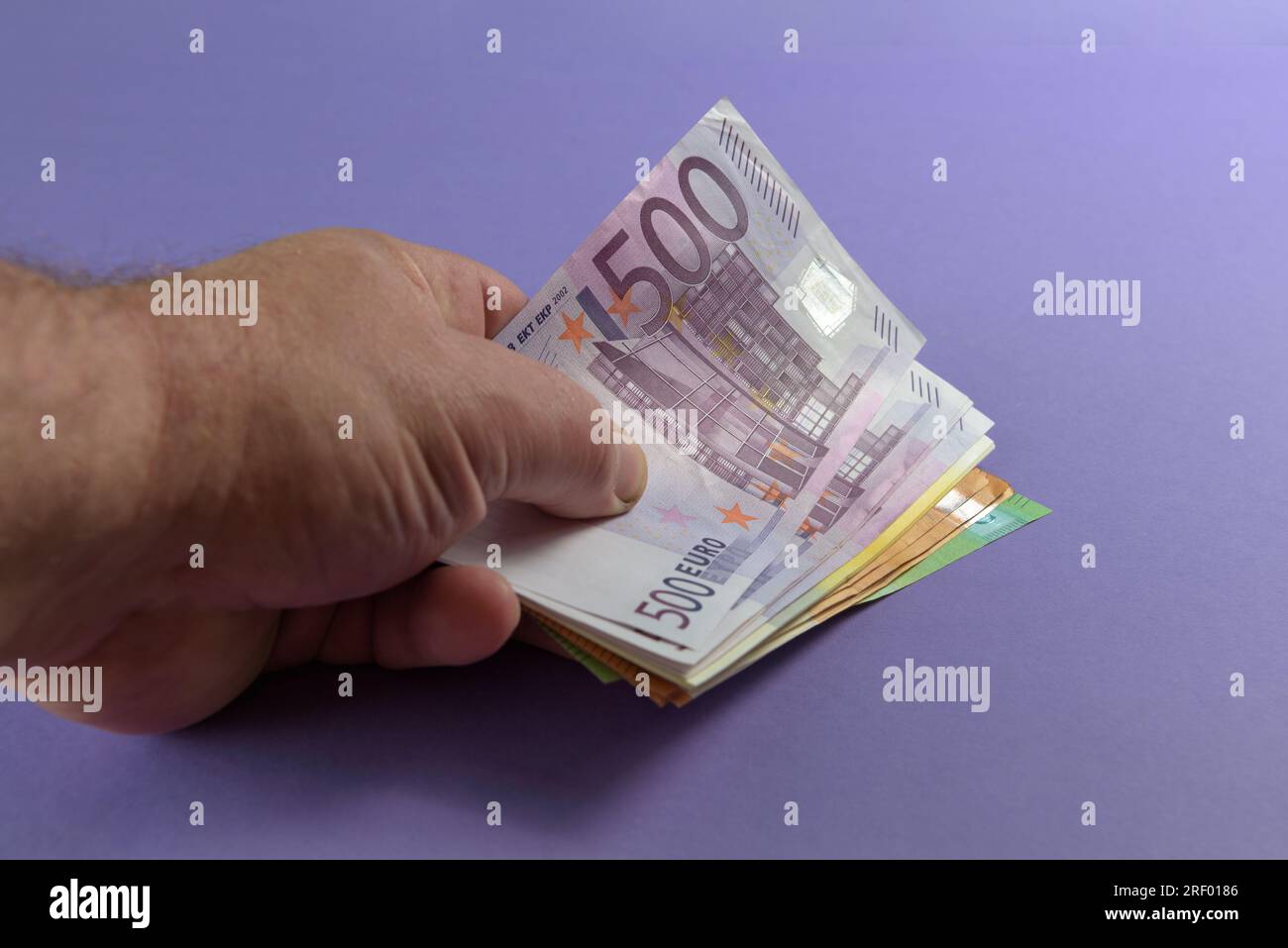 Euro payment. Large banknotes in the hand. Money on the purple ...