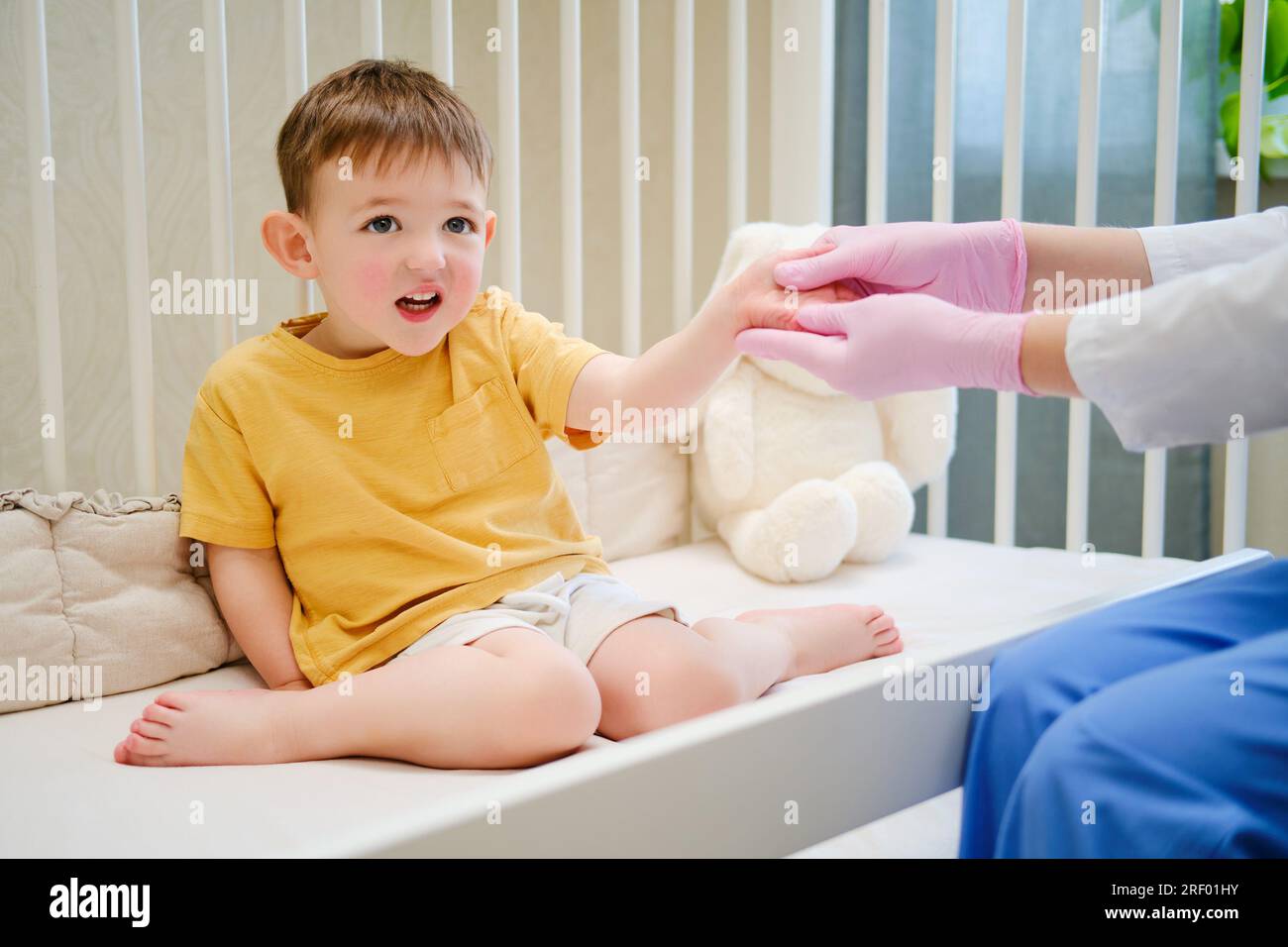 Doctor does gymnastics and hands massage to a toddler baby. Nurse in ...
