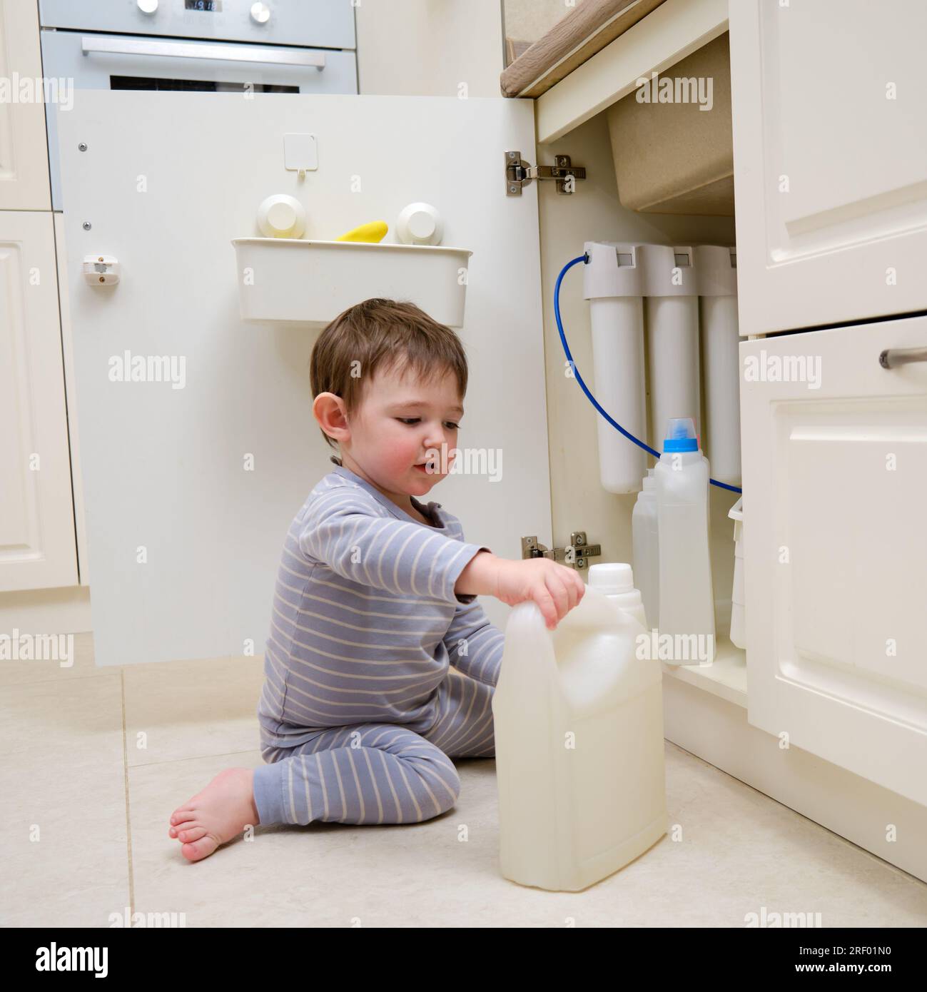 A child is playing with chemical cleaning products under the sink in ...