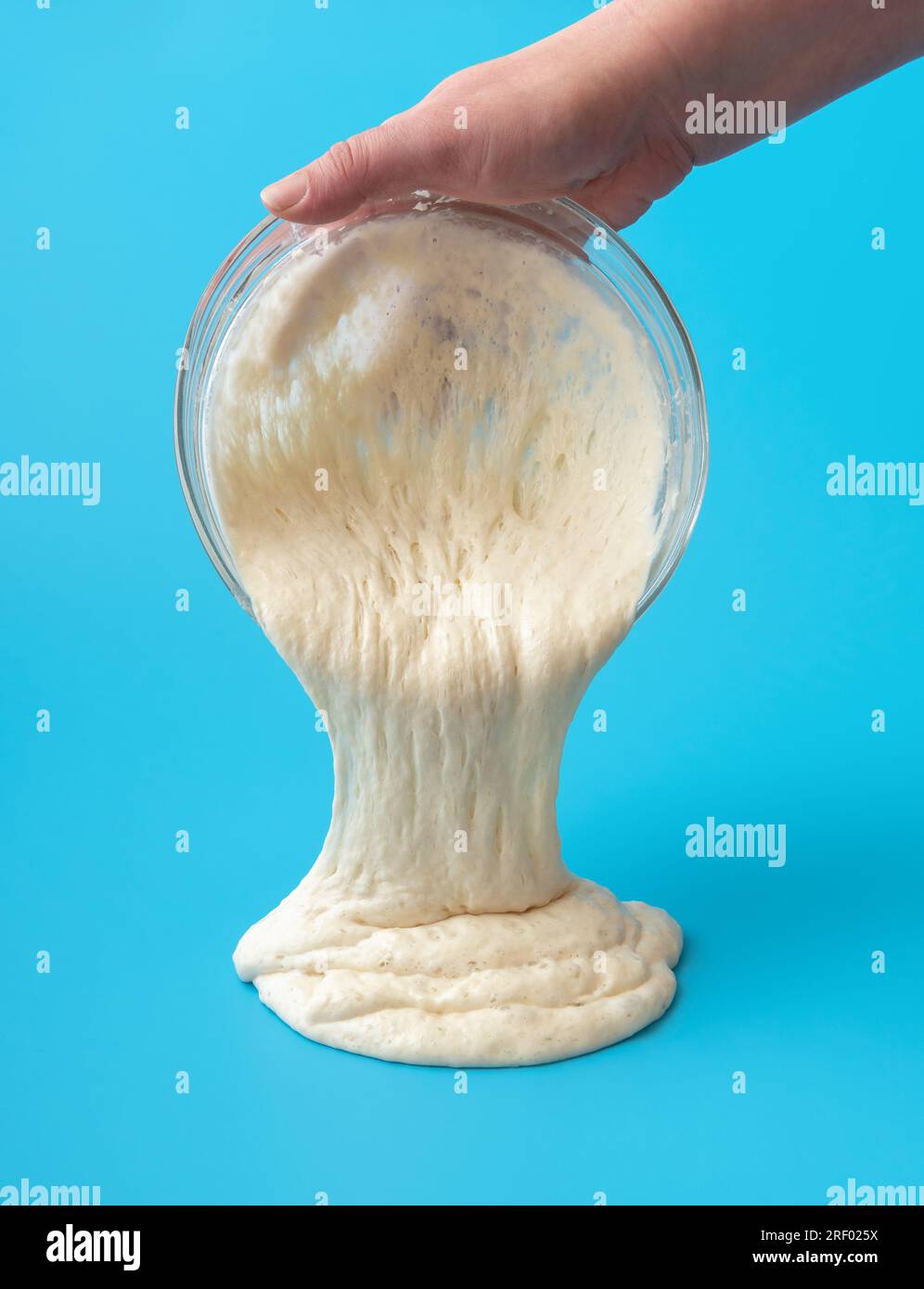 Pouring sourdough discard from a bowl directly on the blue table ...