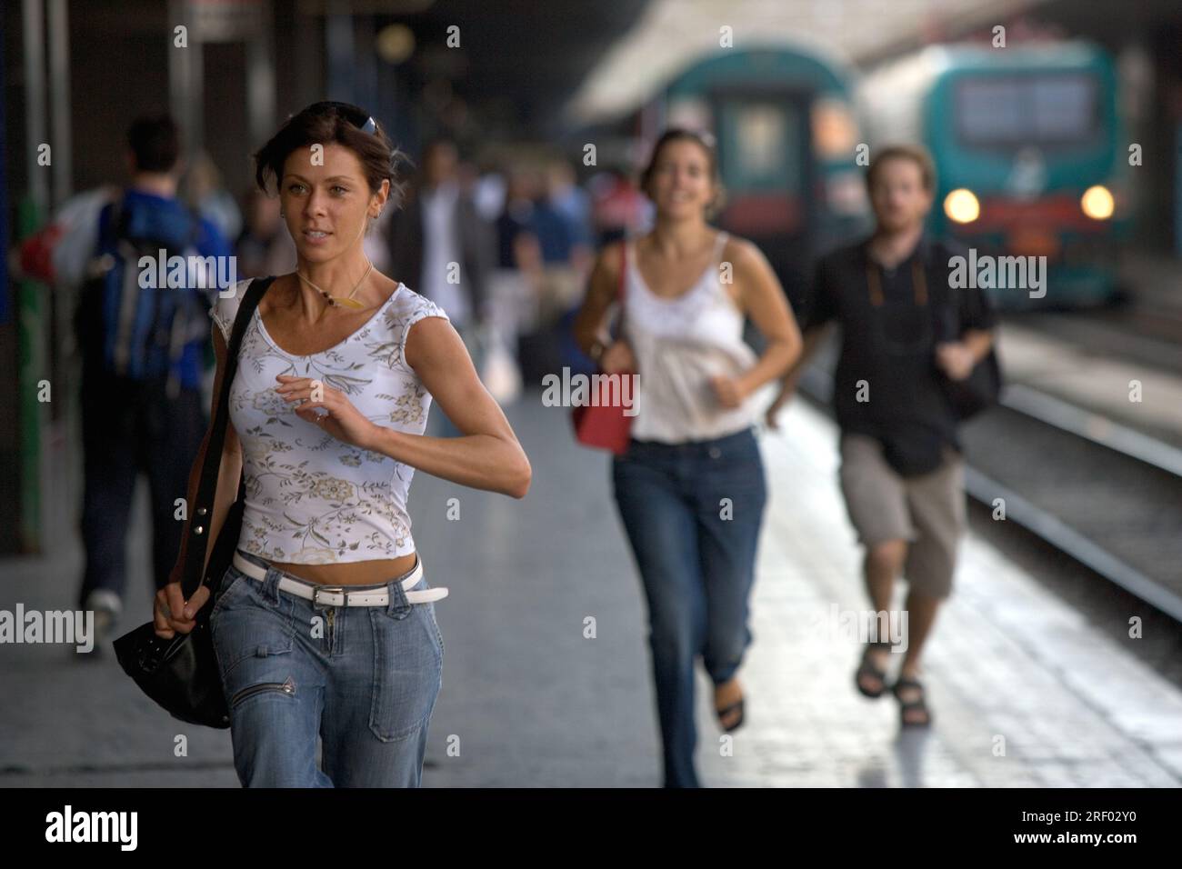 People running on a train platform, likely hurrying to catch a train ...