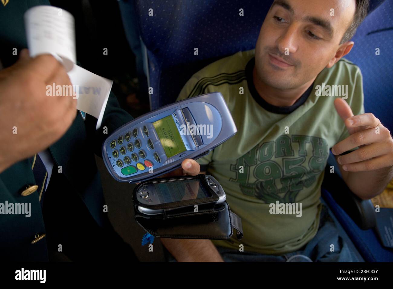 A person using a handheld payment terminal on a train for a transaction ...