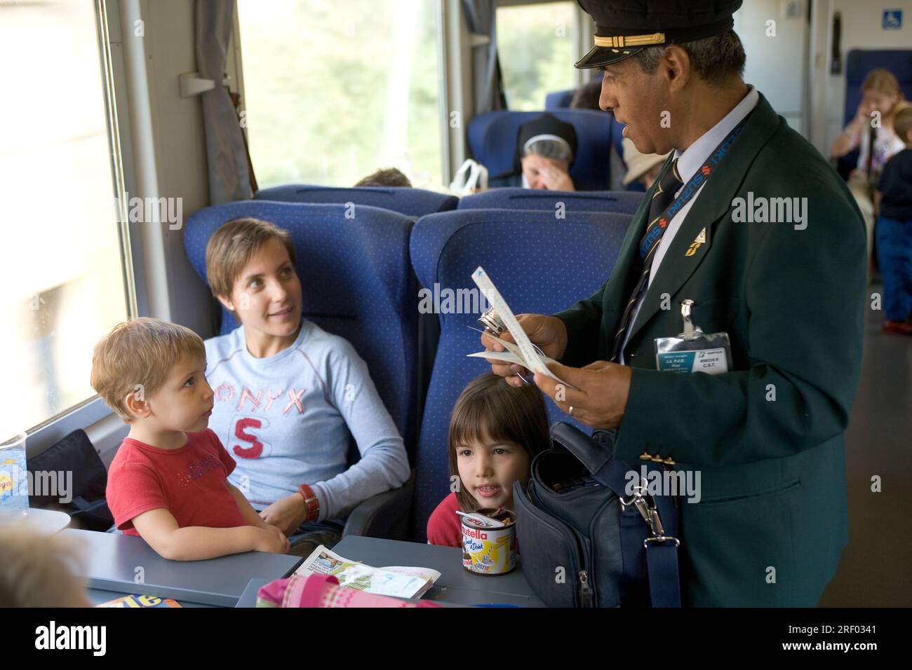A ticket inspector checks tickets for a family on a train in Europe ...