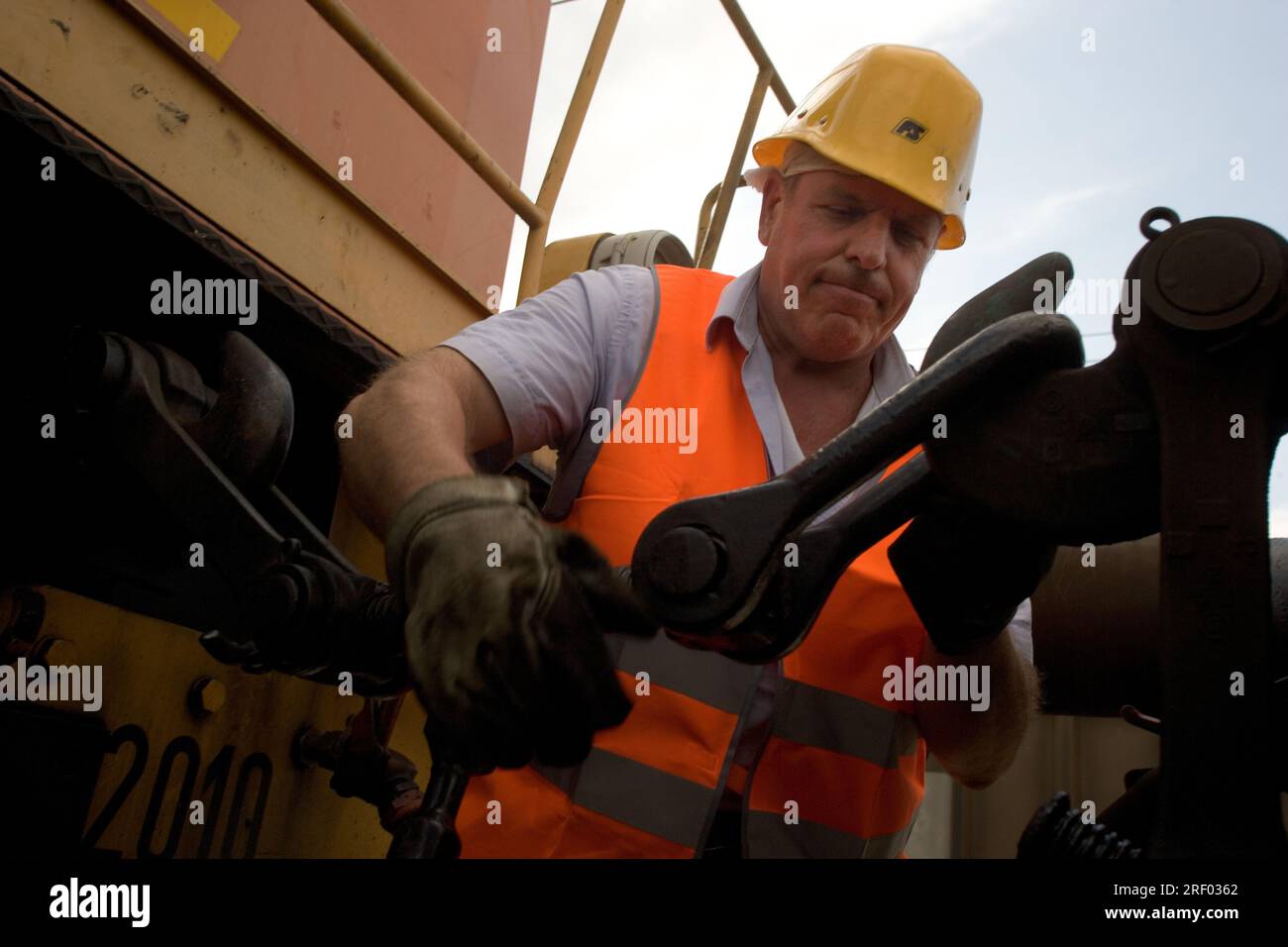A maintenance worker at Milan railway depot uncoupling a train and ...
