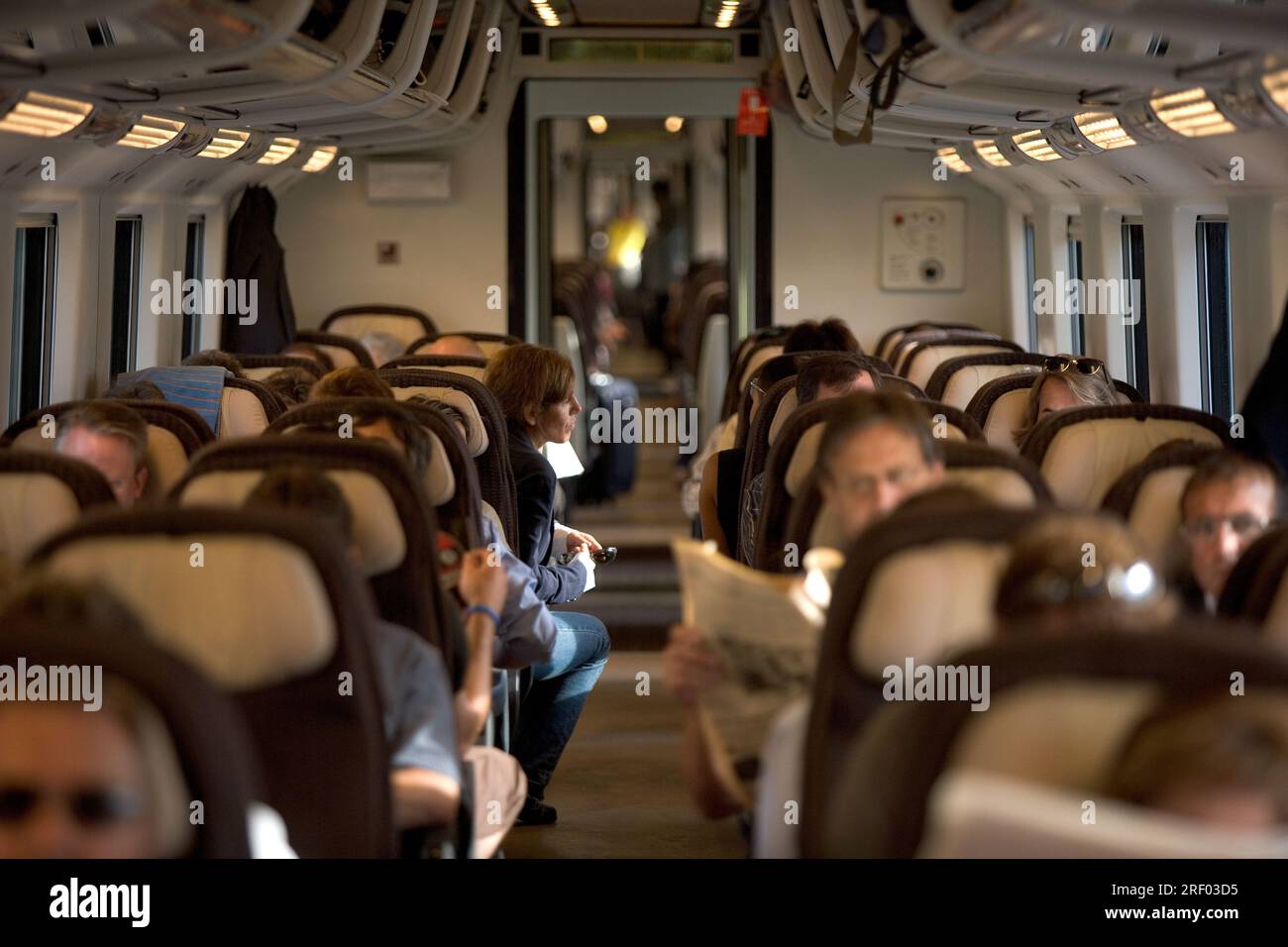 Passengers seated inside a modern train carriage, some reading or ...