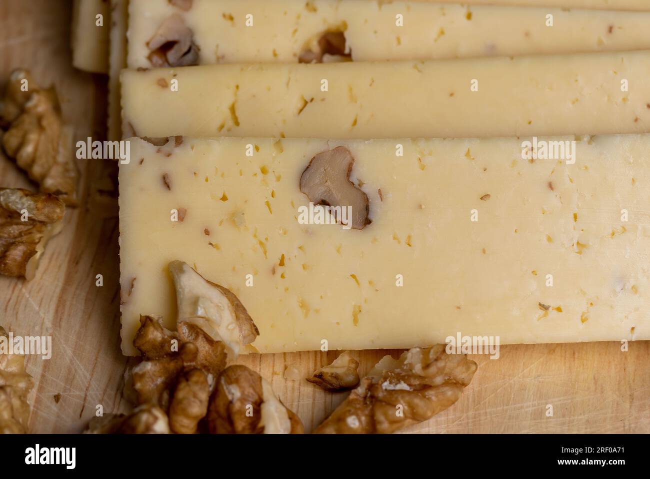 Sliced piece of milk cheese with walnuts, crushed and chopped walnuts ...
