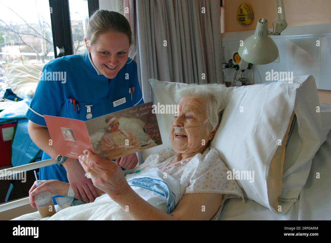 An nurse reads a get-well card with a patient at an NHS hospital in ...