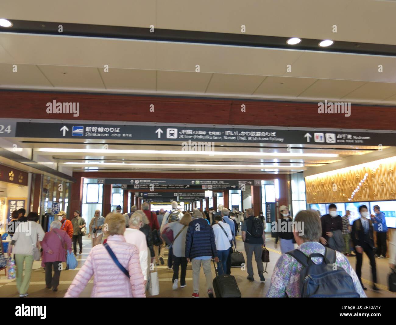 Passengers follow the overhead signs to the Shinkansen or Bullet Train ...