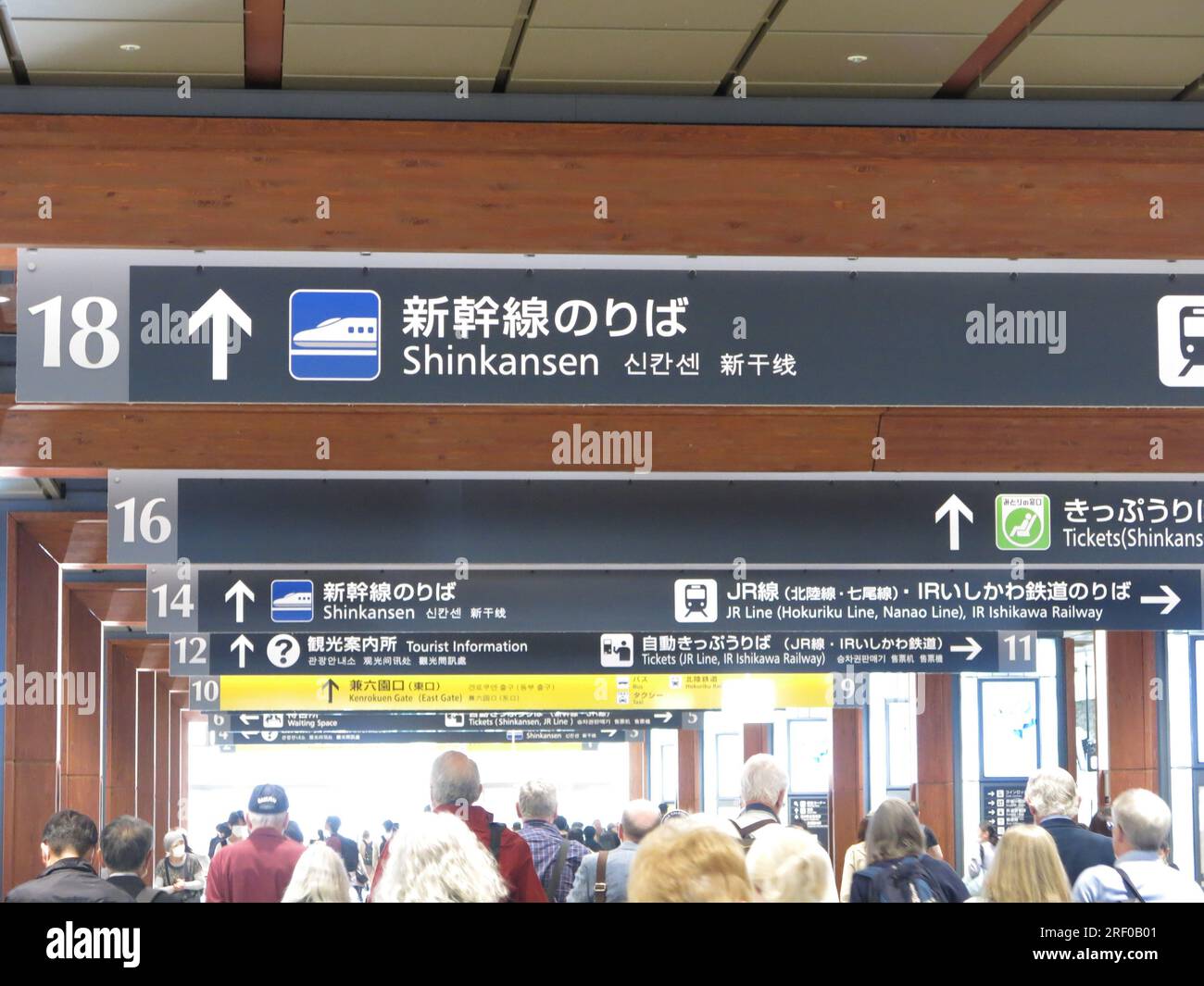 Passengers follow the overhead signs to the Shinkansen or Bullet Train ...