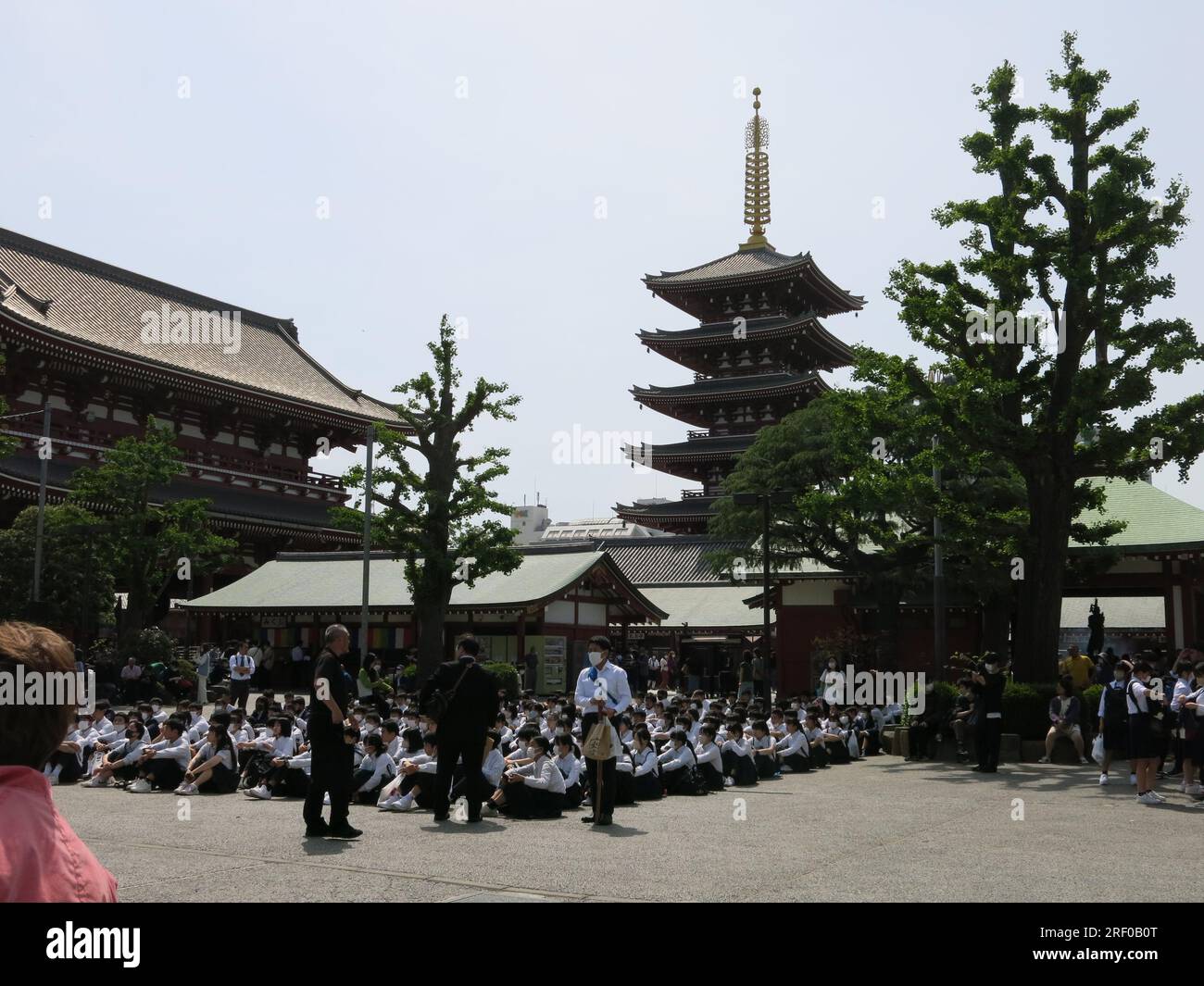 Large party of Japanese school children in uniform are seated on the ...