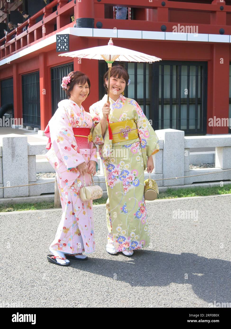 Two women in traditional Japanese dress, kimonos and a parasol, pose ...