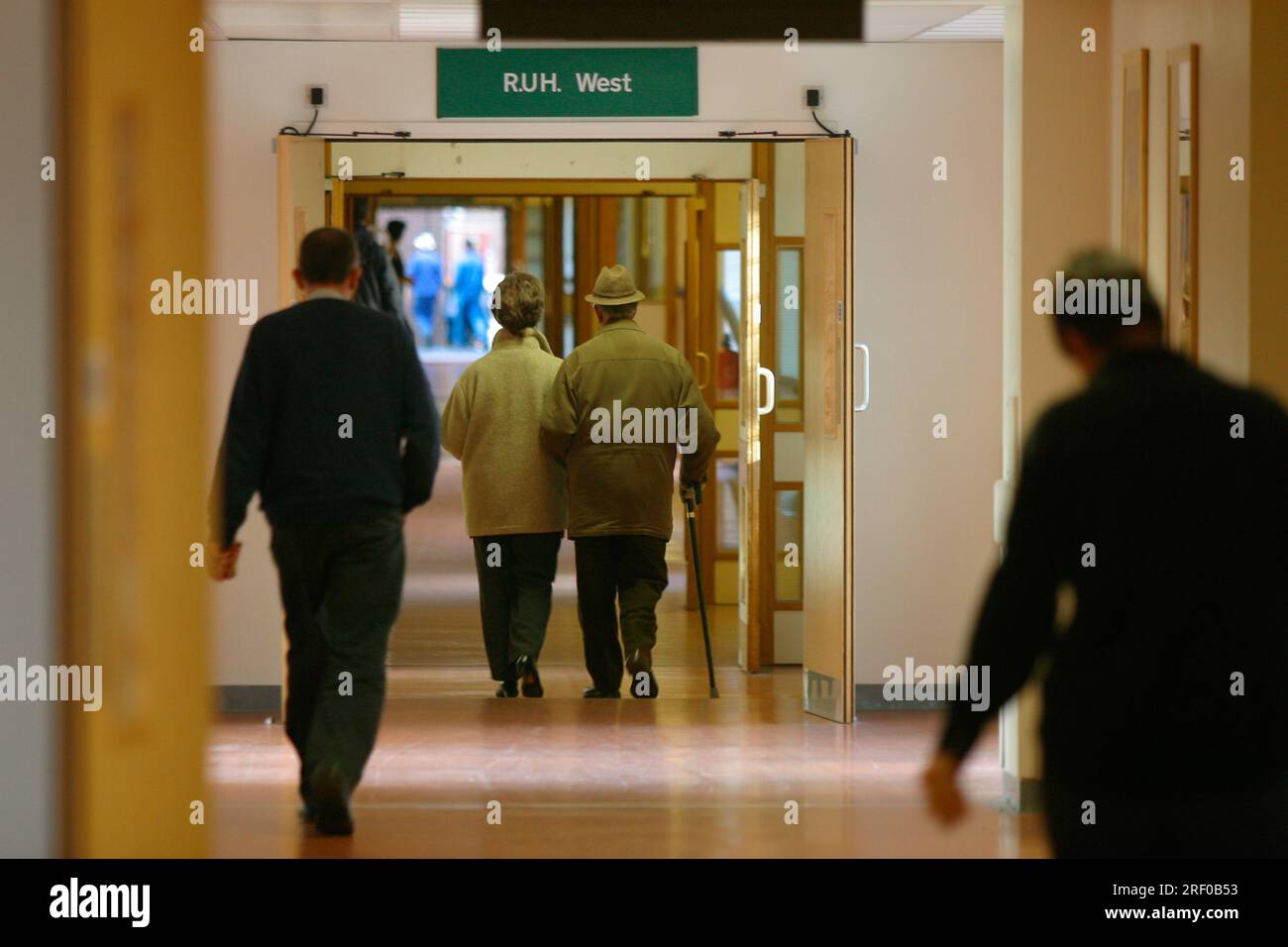 People walking through the hallway of a hospital with a sign reading 'R ...