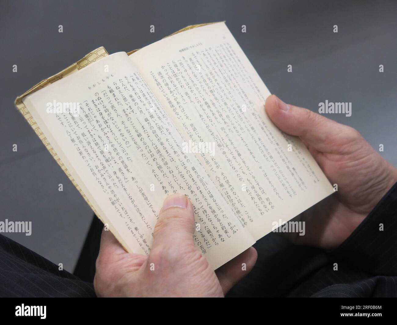 Close-up of Japanese script on the page of a small book held in a pair ...