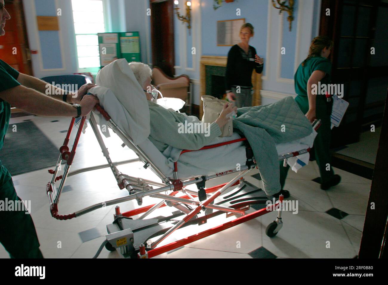 Patient on a stretcher being wheeled through a hospital corridor by staff Stock Photo - Alamy
