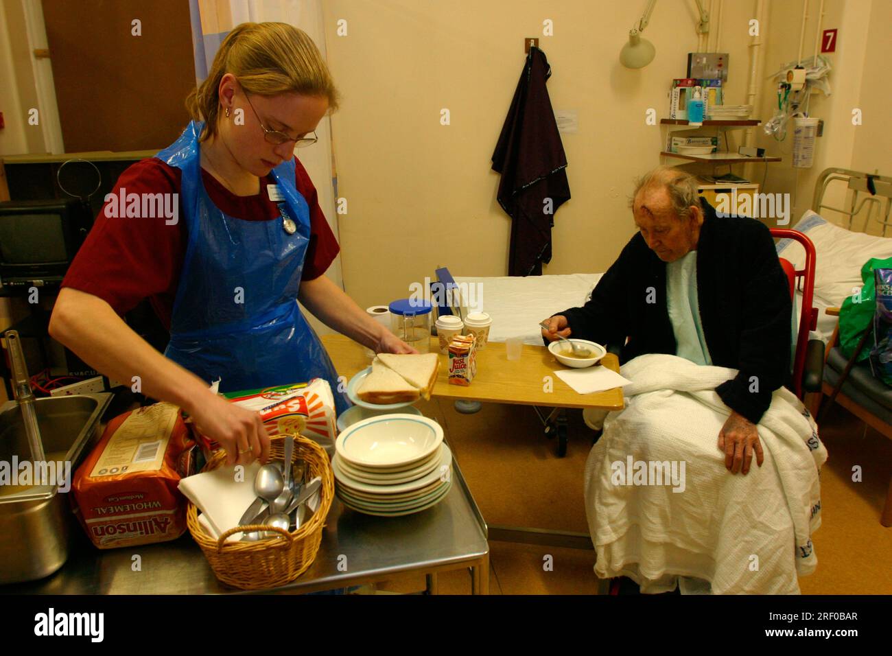 A healthcare worker prepares food for a patient in a hospital ward ...