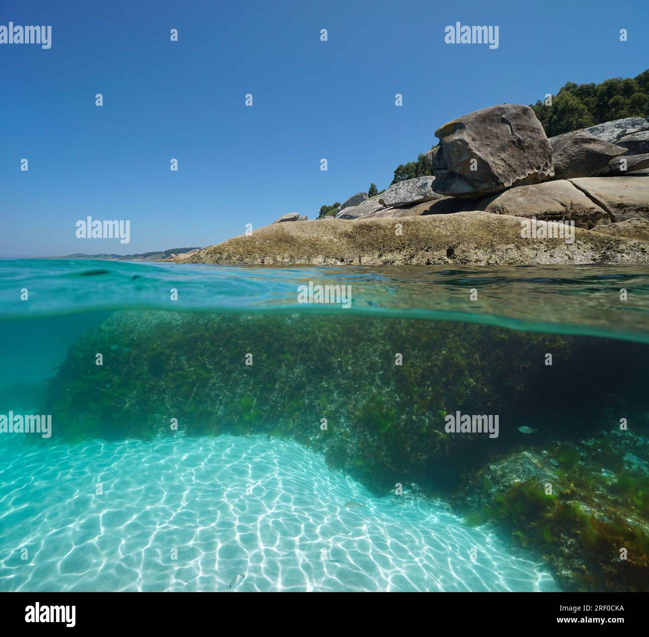 Boulders on the sea shore, split view over and under water surface ...