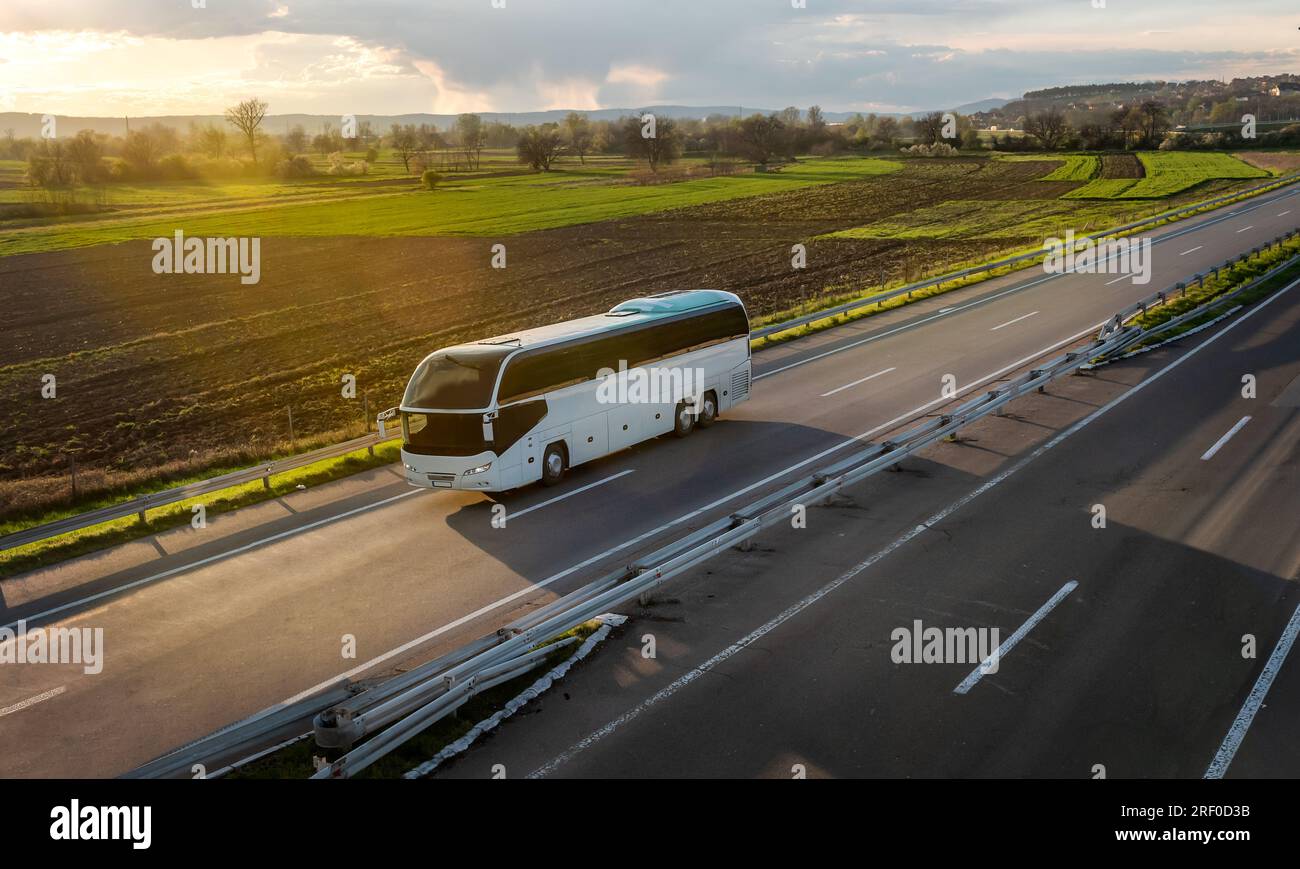 White Modern comfortable tourist bus driving through highway at bright ...