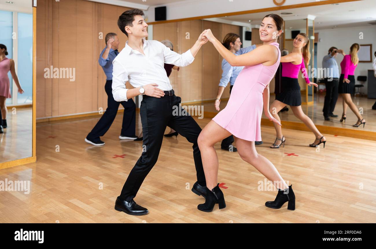 Couple of young dancers rehearsing ballroom dances in dance studio ...