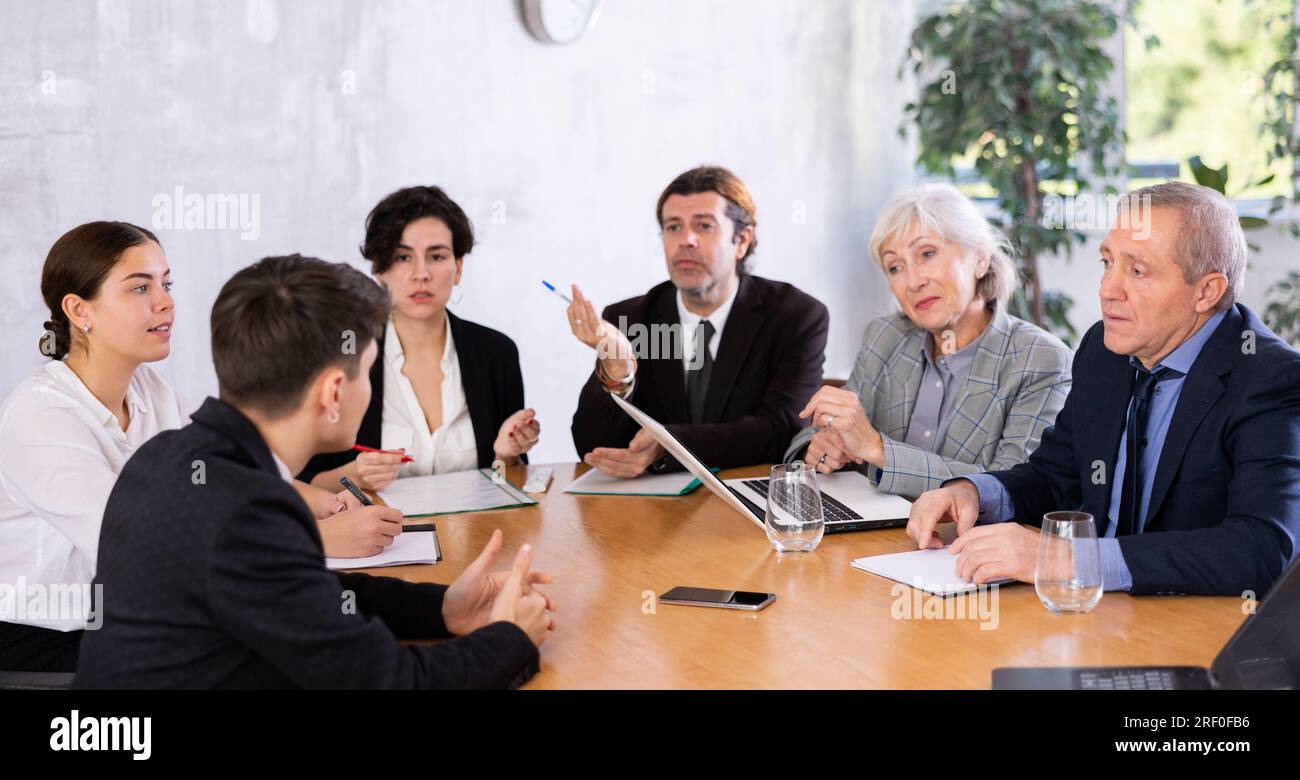 Concentrated young adult old office workers discussing ideas while ...