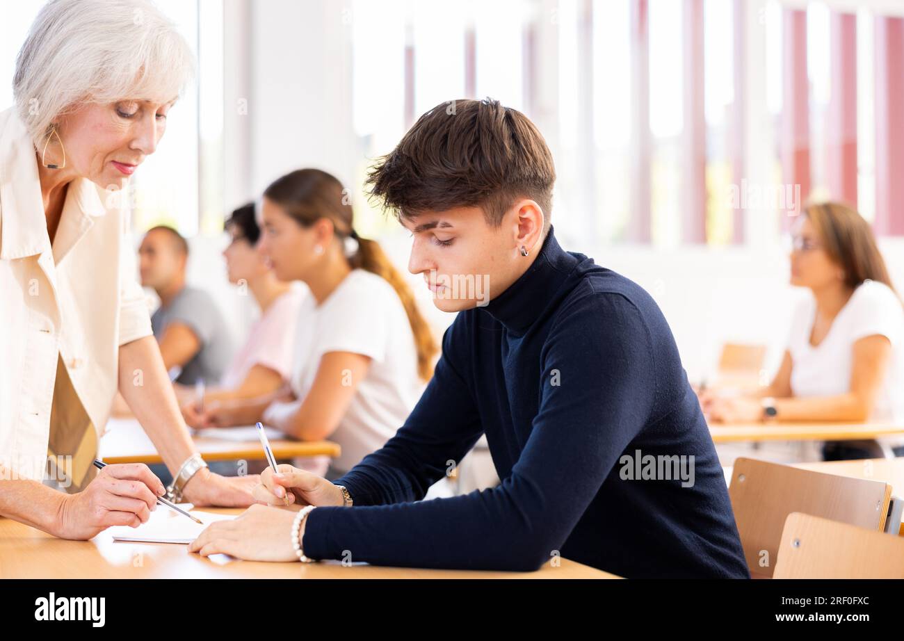 Female teacher helps student complete an assignment in university class ...