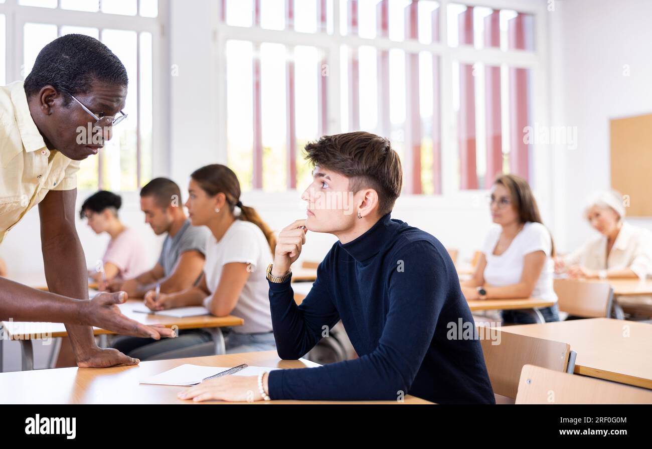 Young man listening to teacher during classes in university Stock Photo ...