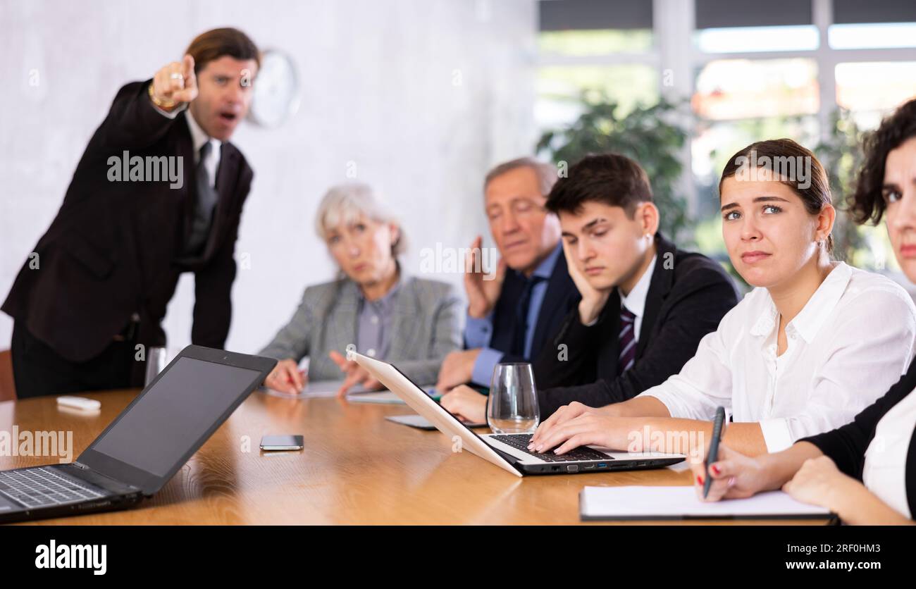 Upset young girl sitting with colleagues scolded by angry boss Stock ...