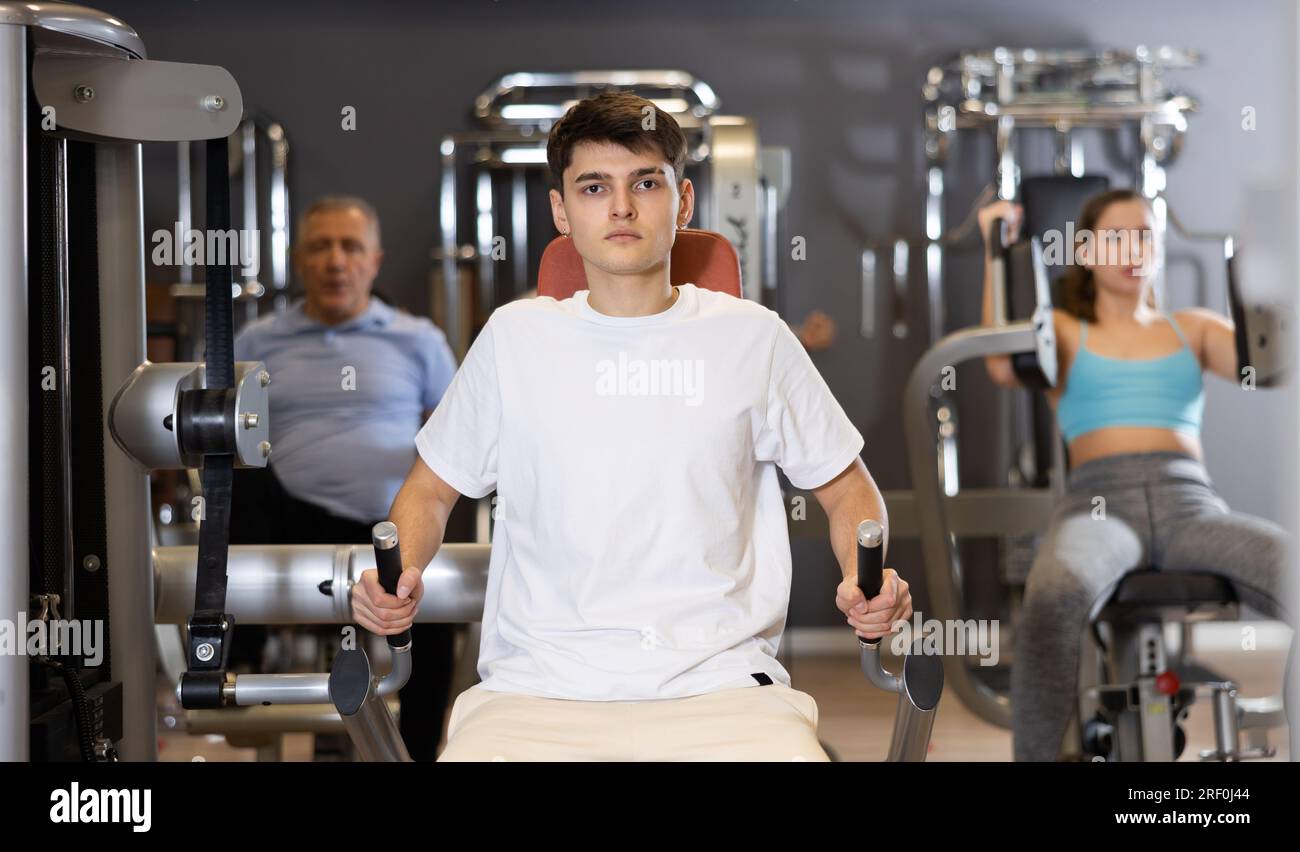 Concentrated guy doing triceps press in gym machine Stock Photo - Alamy
